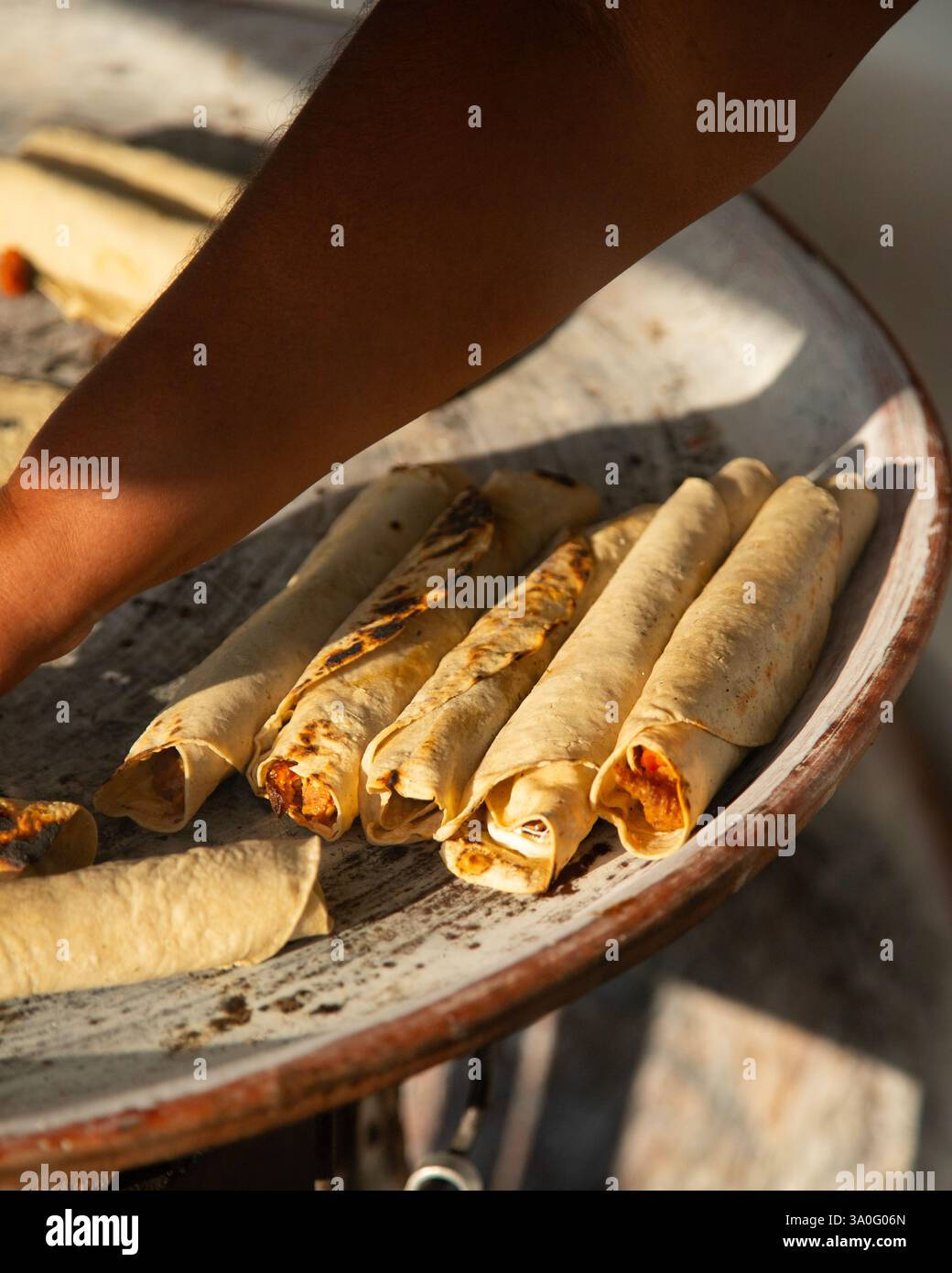 A woman cooking tortillas, flautillas and Mexican memelas on a comal on ...