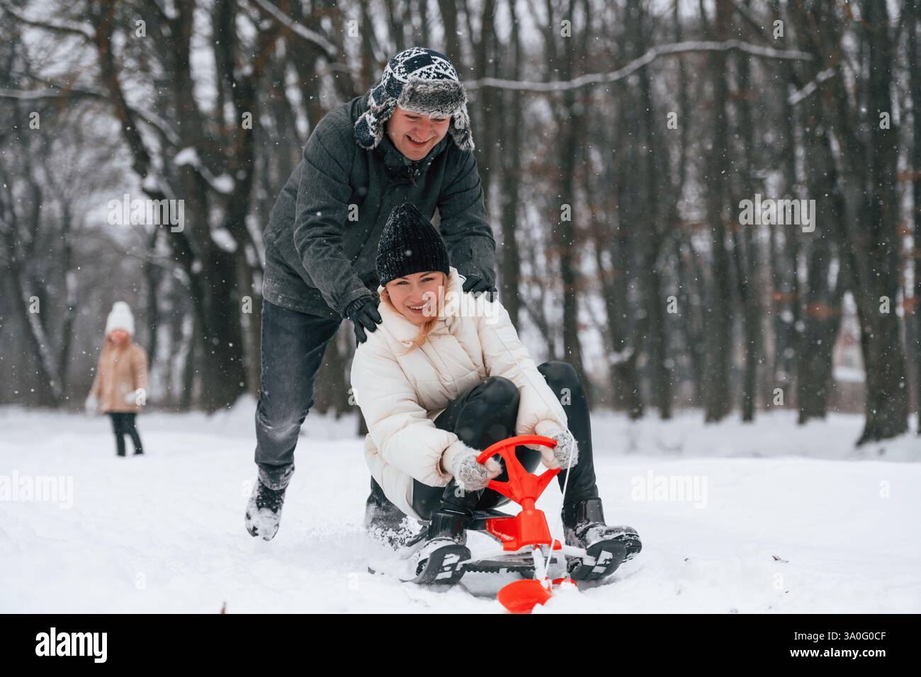 Sled ride. Mother and father is with daughter have walk outdoors at the ...