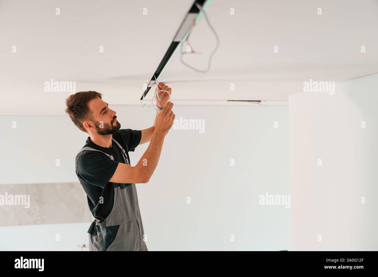 Installing lighting equipment on the ceiling. Man is working indoors at ...