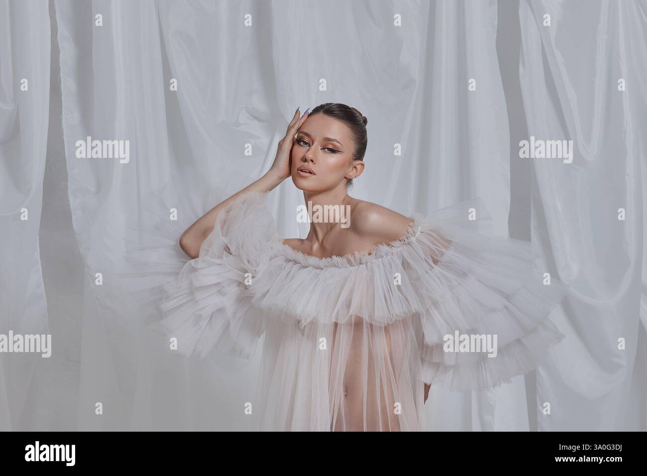 model stands elegantly in an airy white gown featuring ruffled sleeves ...
