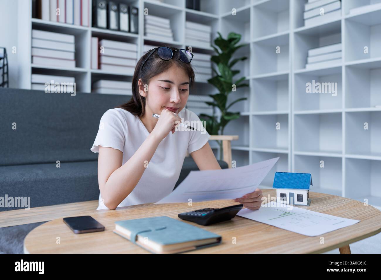 Thoughtful woman reviewing documents while calculating expenses for ...