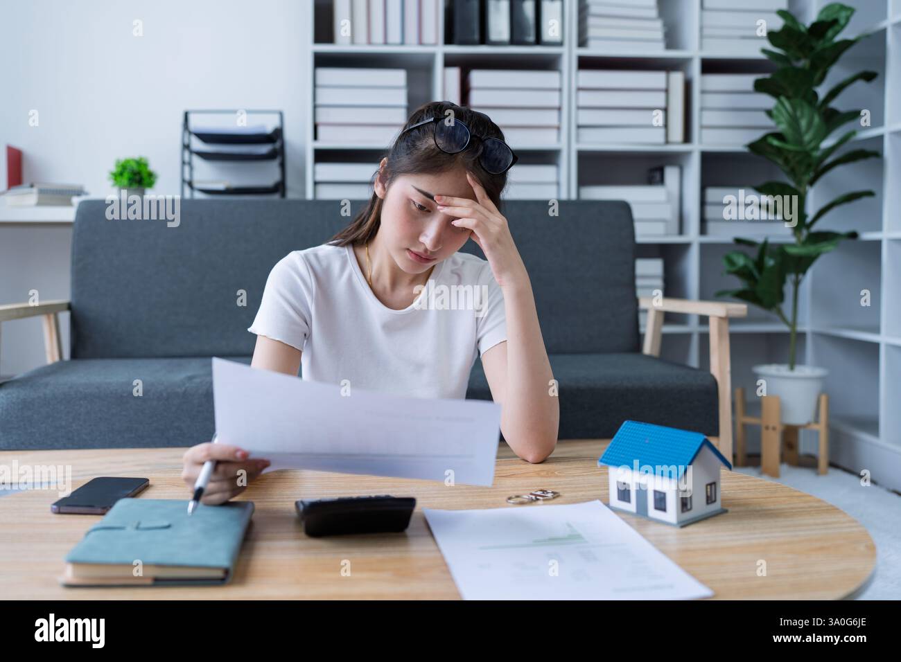 Thoughtful woman reviewing documents while calculating expenses for ...