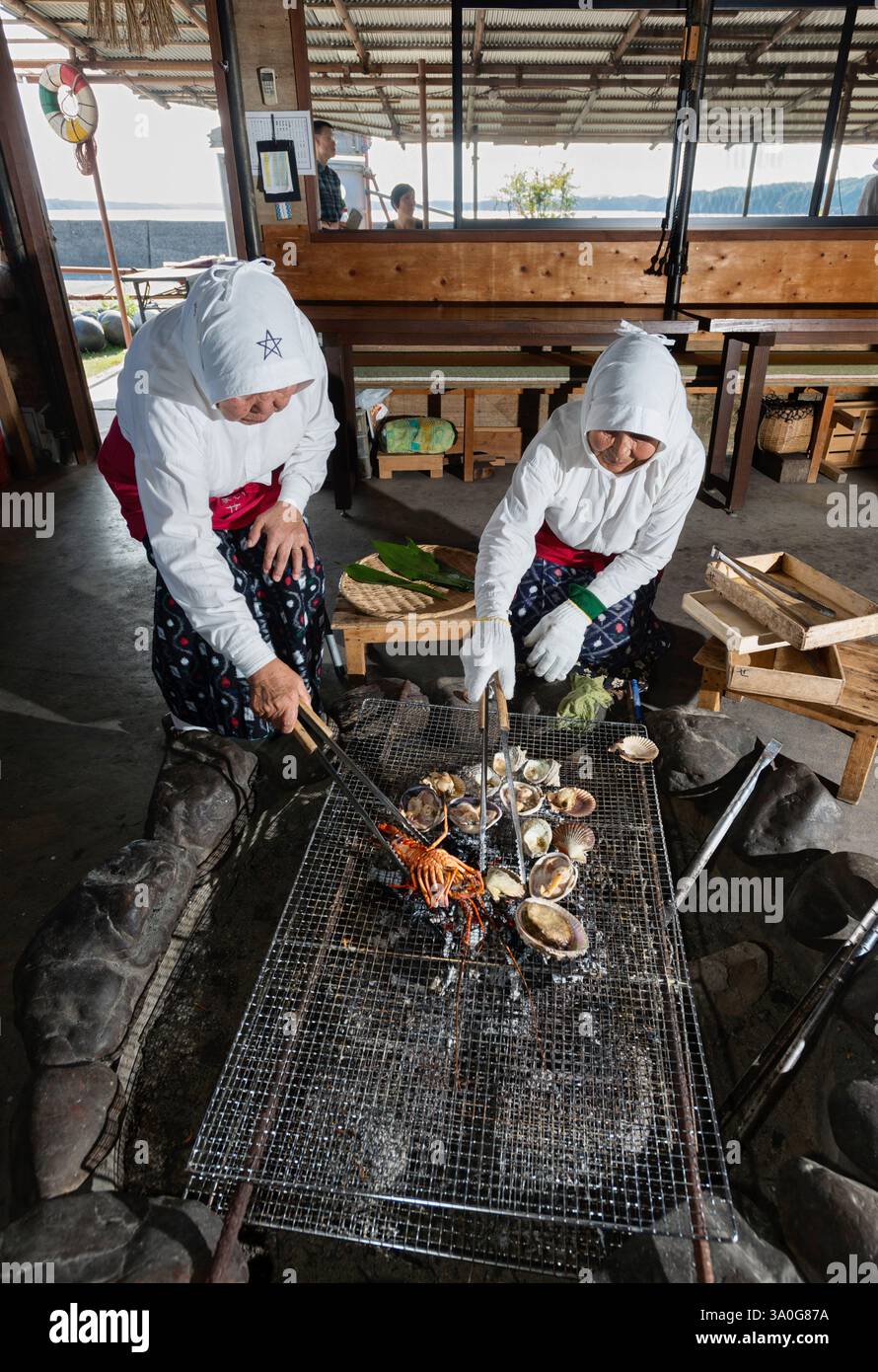 Heiko (left) and Namie Nomura cook seafood on a grill inside the ...
