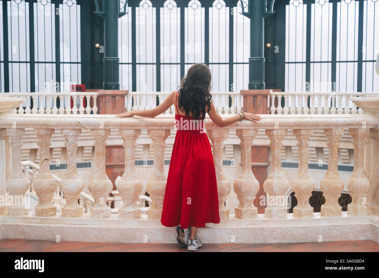 A romantic princess stands gracefully in a red dress inside an ancient ...