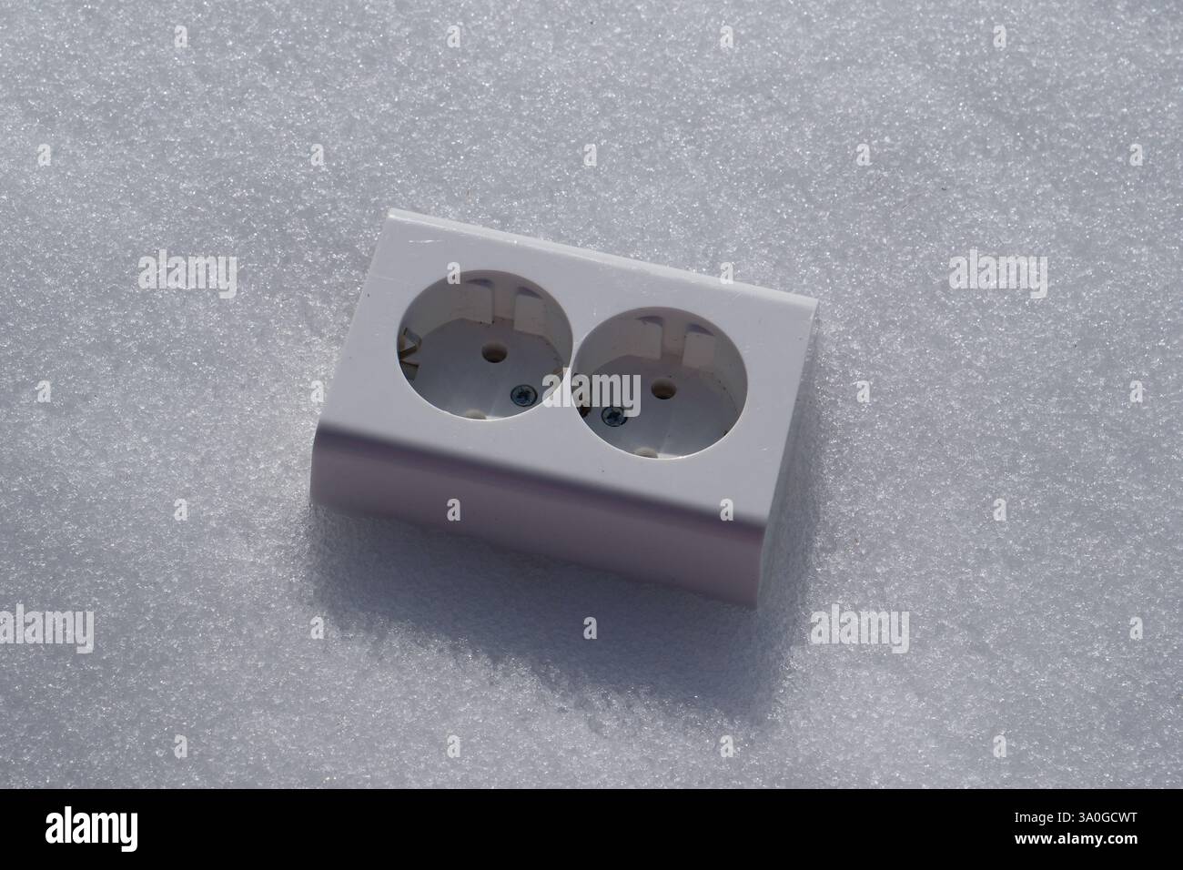 Electrical socket on the snow close-up. Electricity concept. Power outlet on a white background ...
