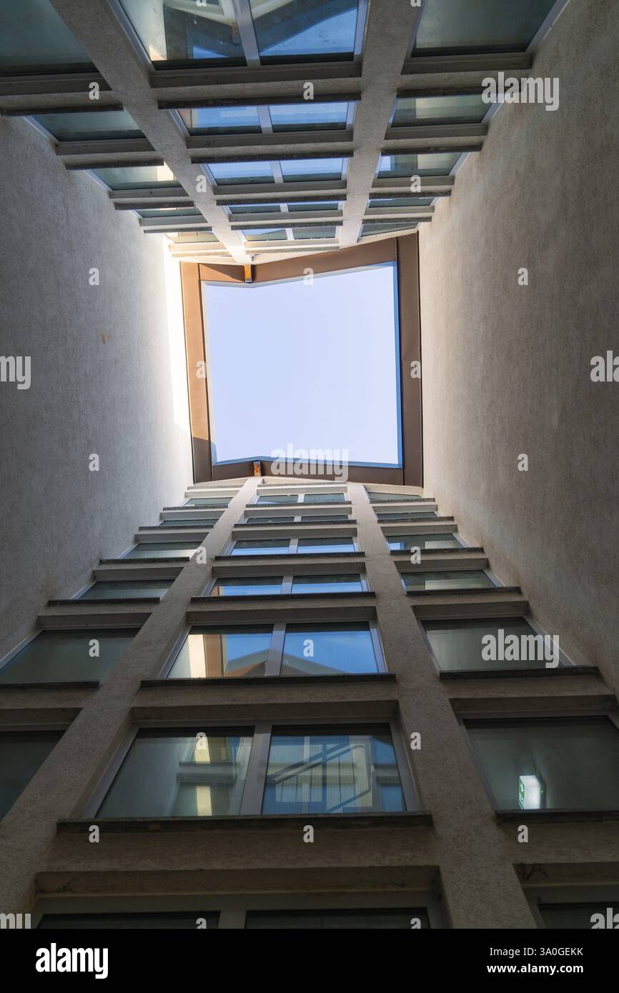 View upwards in a building courtyard, surrounded by high facades and a ...