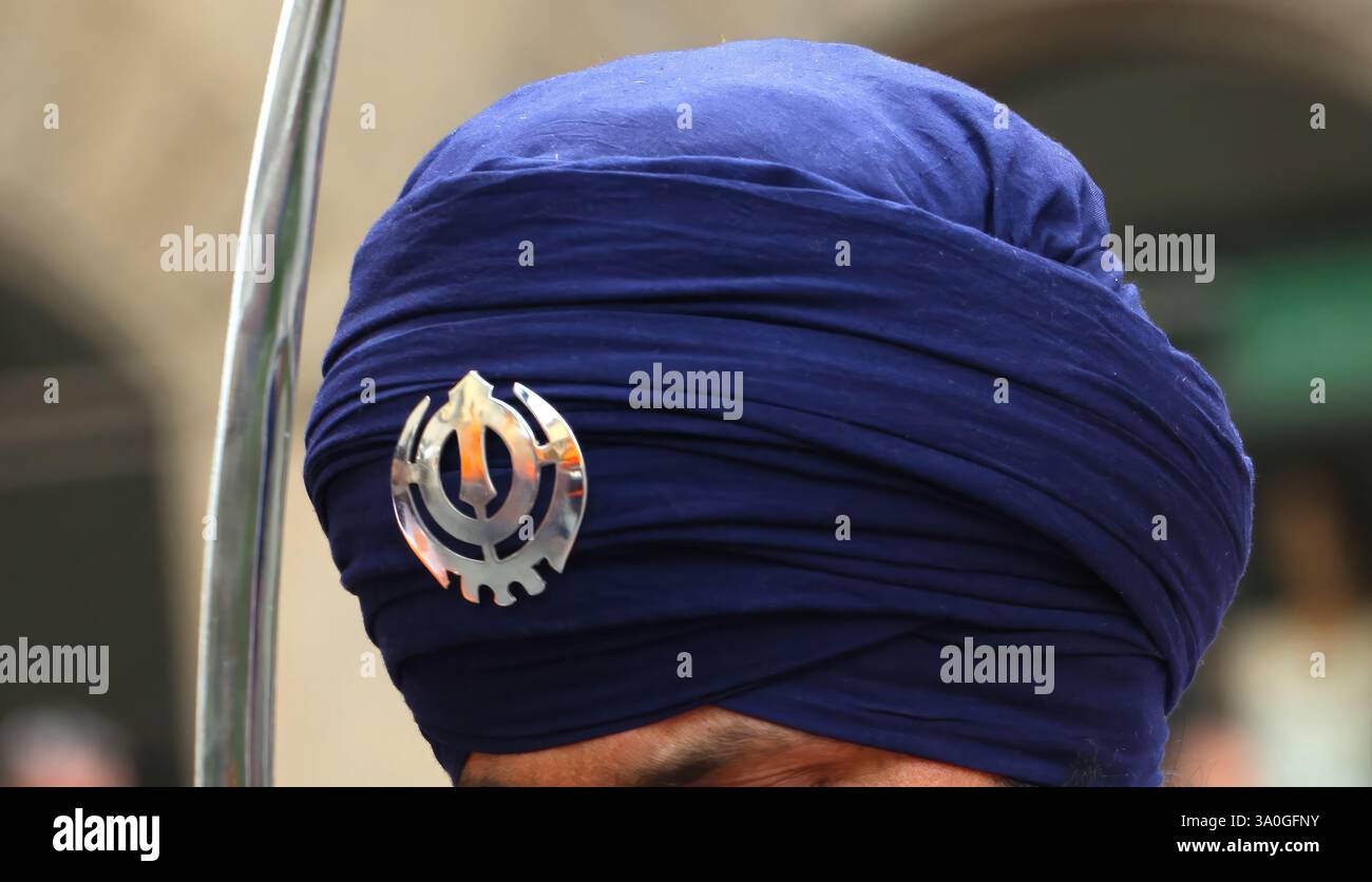Close up of a Sikh man wearing a blue Dastar adorned with the Khanda ...