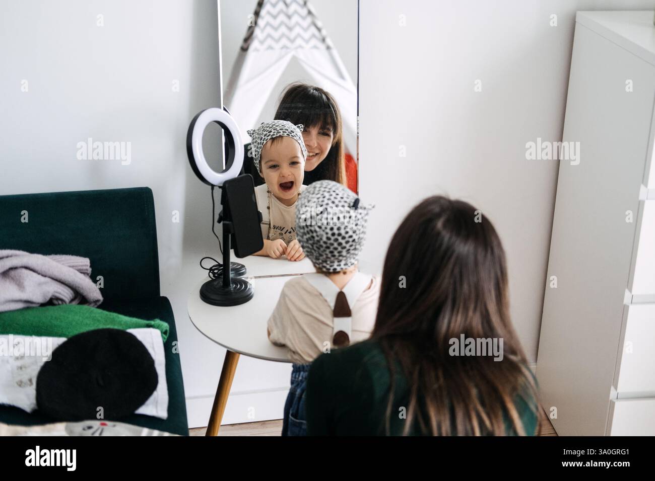 Toddler exploring self-discovery through mirror play with mother. Child ...