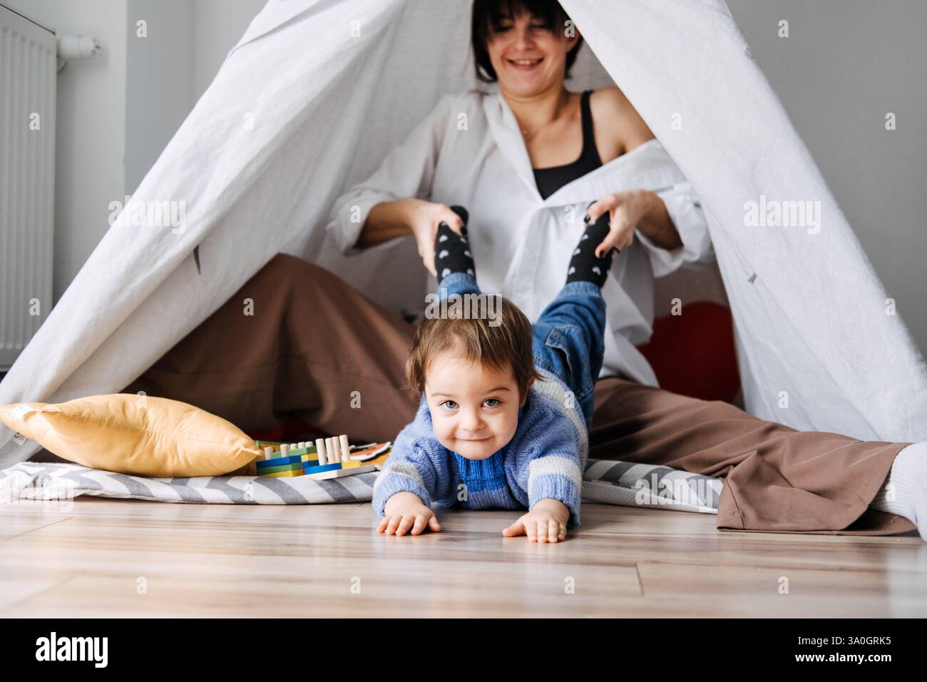 Mother playing with toddler in makeshift indoor tent. Early childhood ...