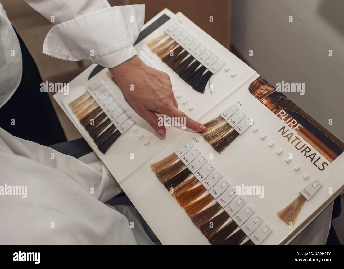 Hairdresser choosing hair dye shades using a professional color palette in a beauty salon. Hair ...