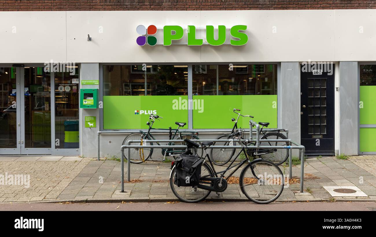 Plus logo sign. Plus is a supermarket groceries store with bikes parked ...