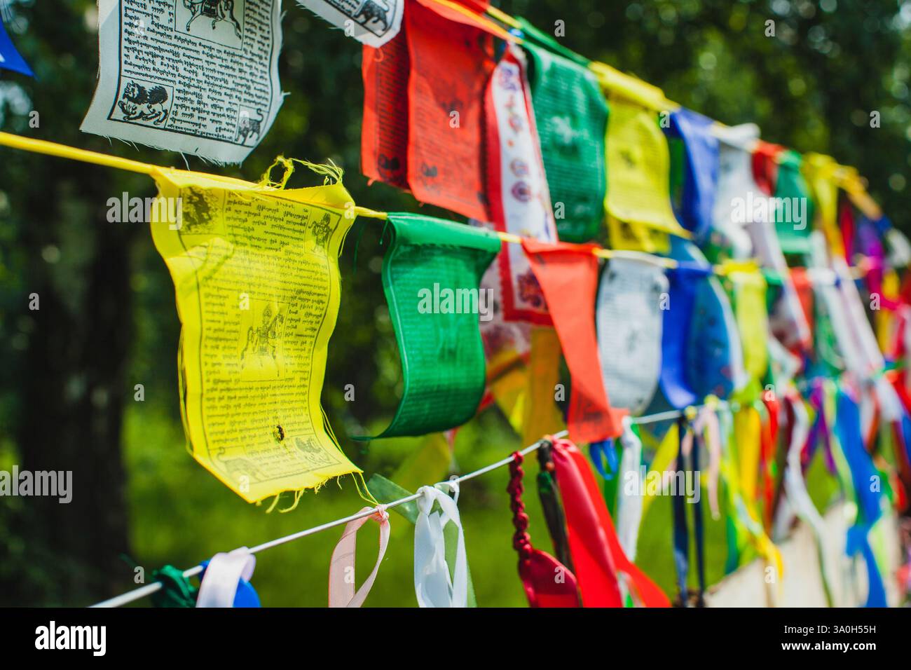 A close-up of colorful prayer flags hung on a line outdoors, gently ...