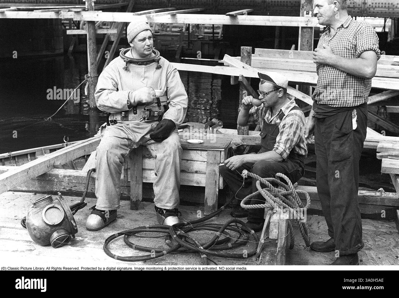 A diver in 1953, sitting in his diving suit and drinking coffee. The ...