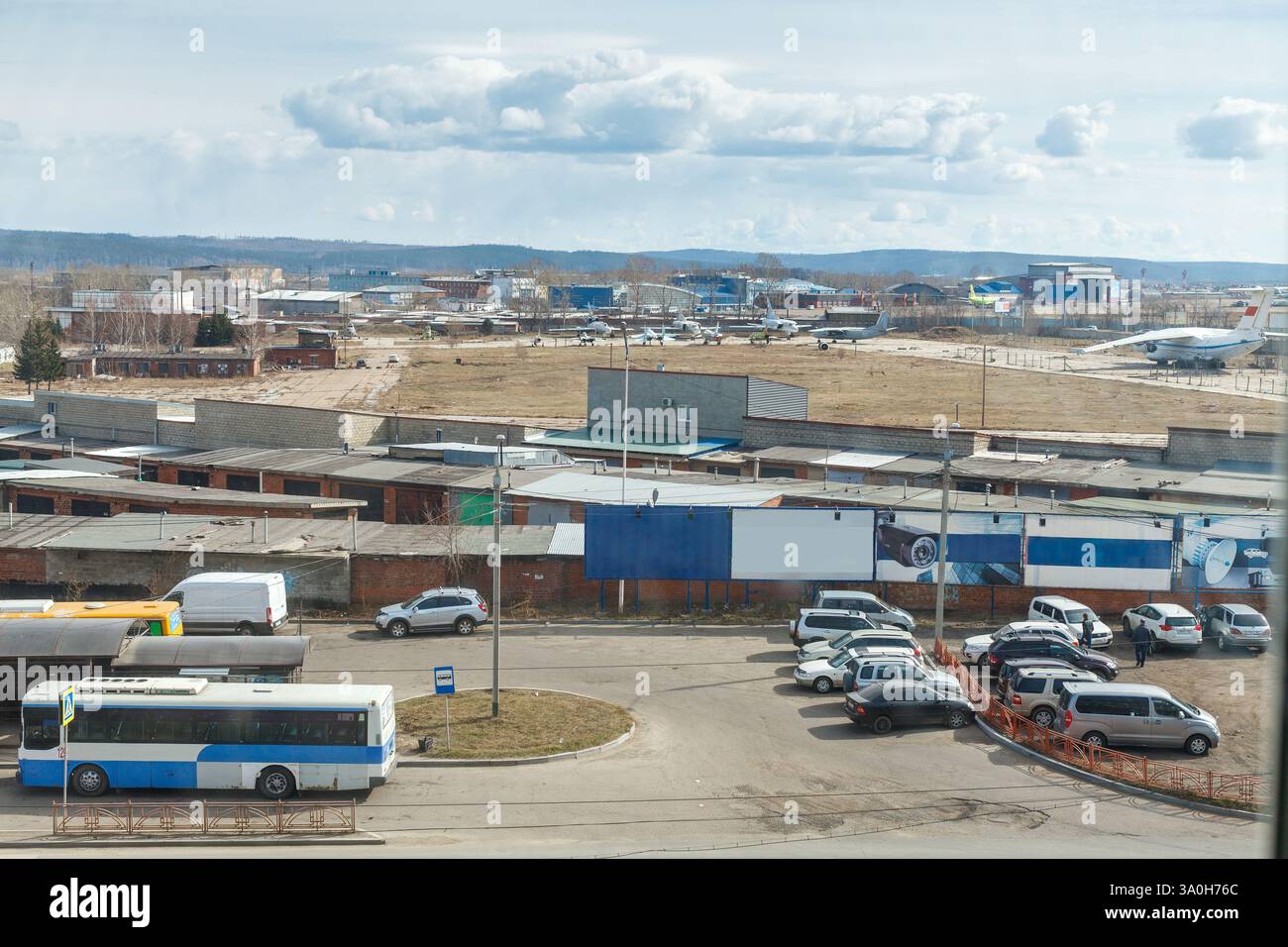 An airport scene with parked planes, vehicles, and industrial buildings ...