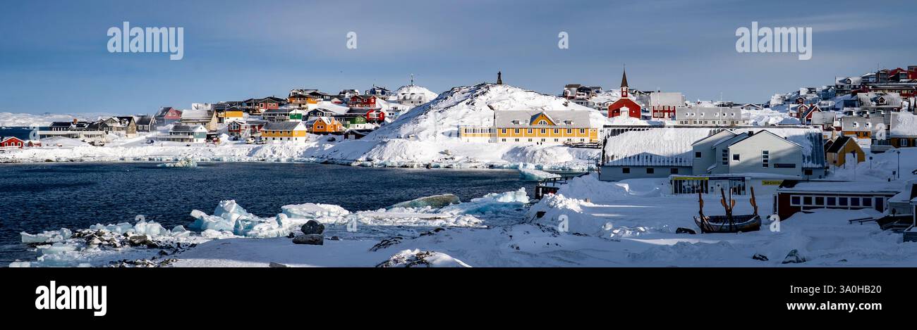 A panoramic view of a snowy coastal town with colorful houses ...