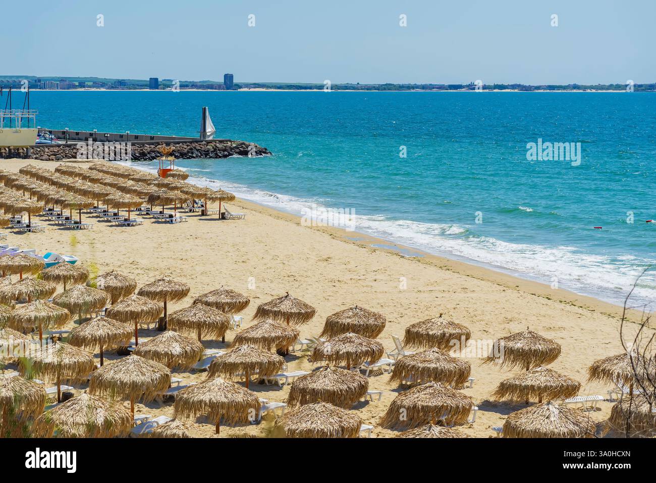 Coastal beach with waves, straw umbrellas, clear blue sky. Peaceful ...