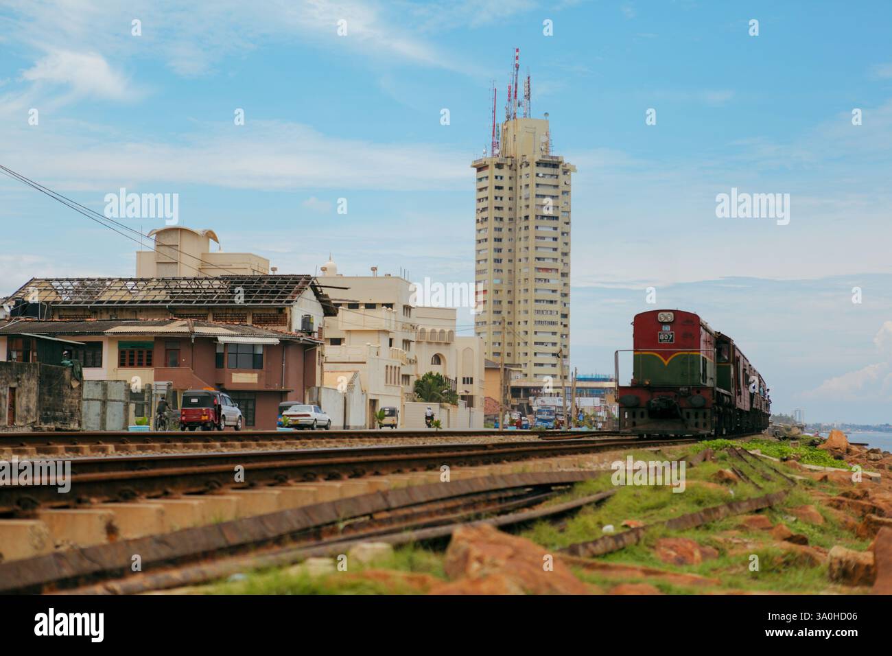 A train moves along railway tracks amidst a mix of buildings and ...