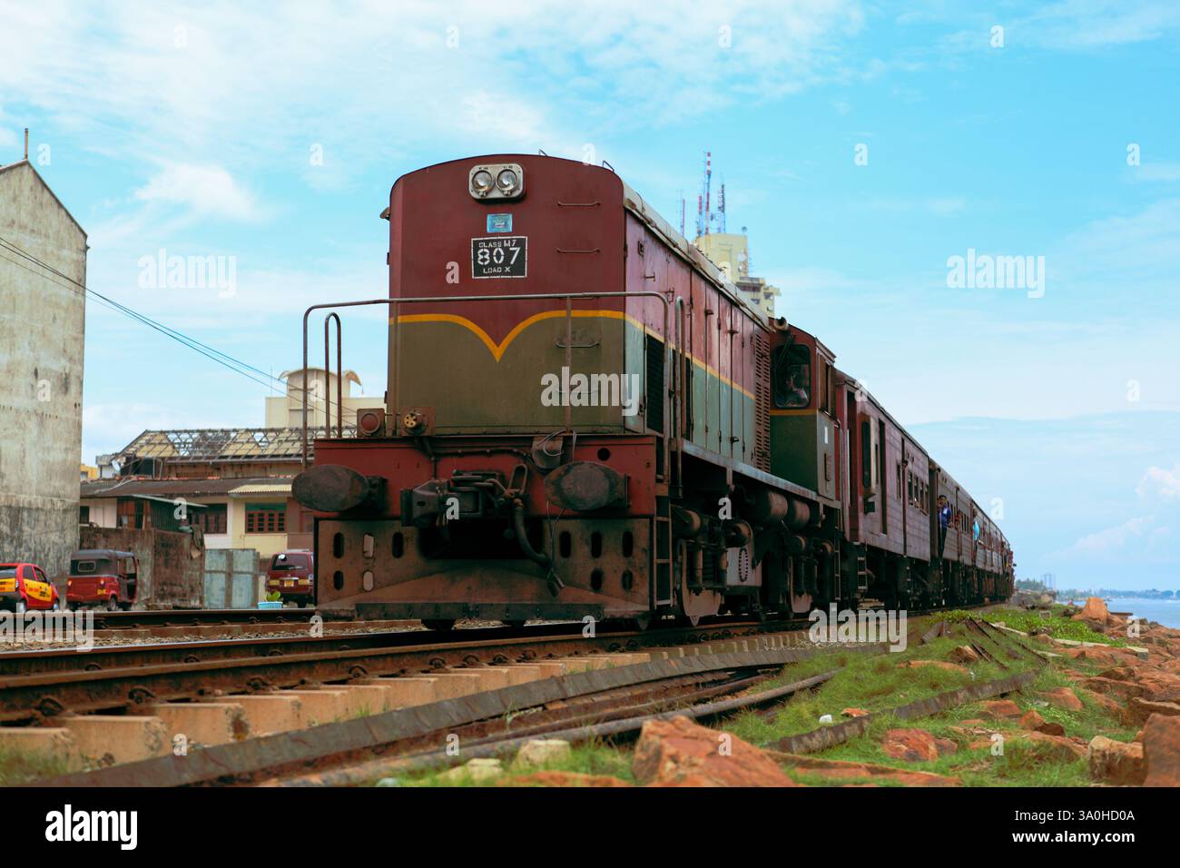 A vintage train travels along tracks in Colombo while colorful ...