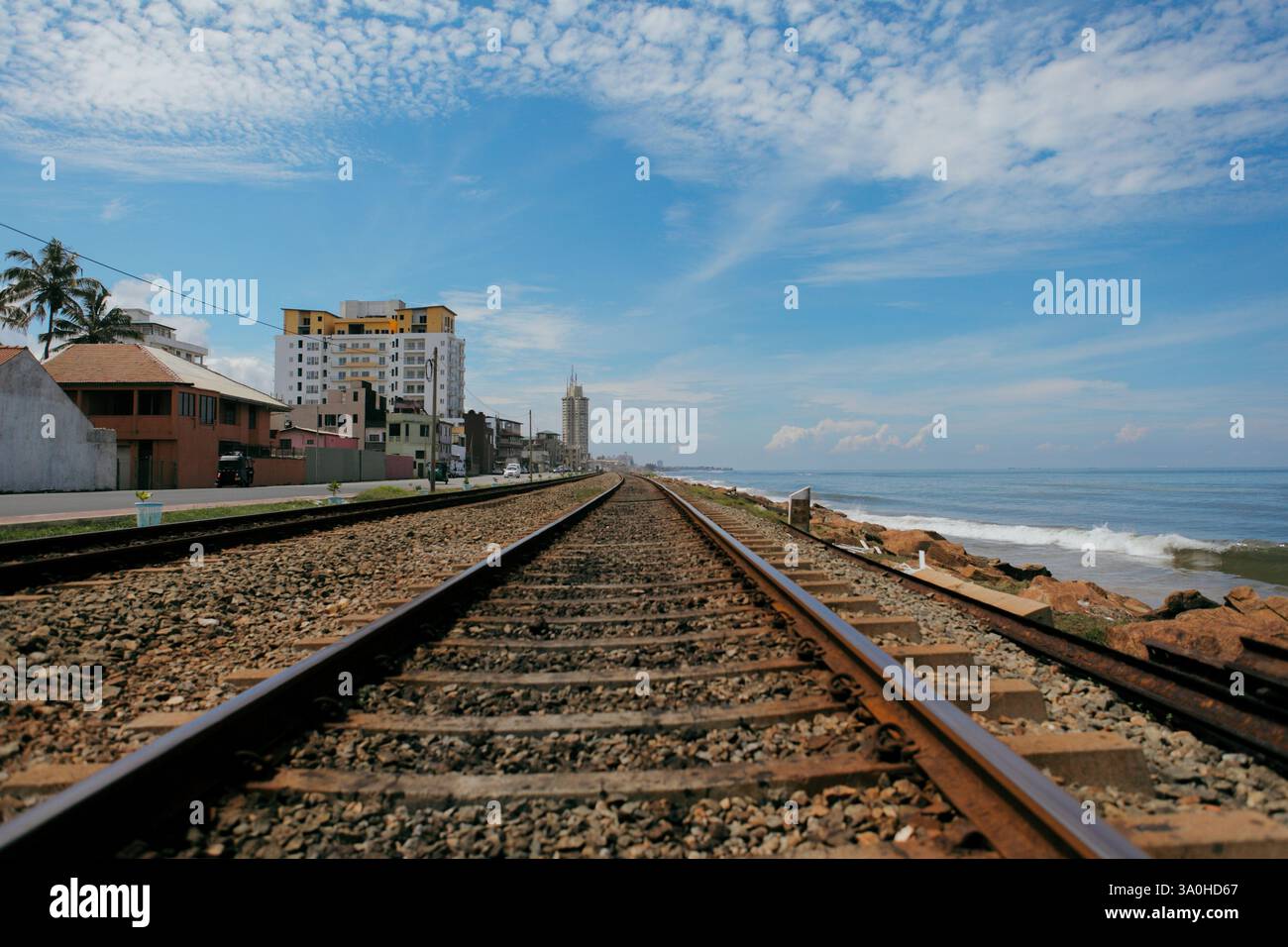 Railway tracks stretch towards the horizon beside the ocean with ...