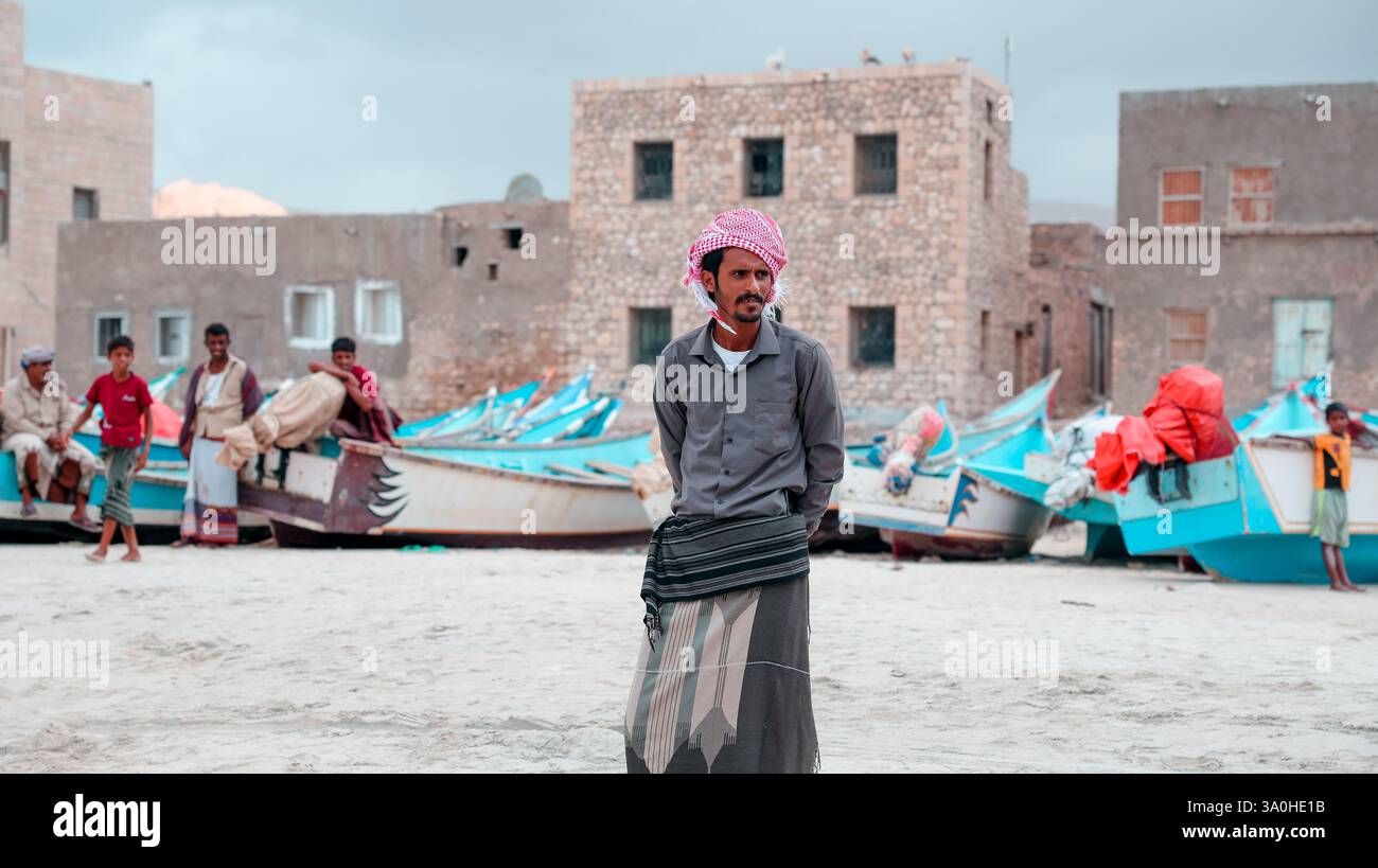 Local men dressed in traditional clothing stand near colorful fishing ...