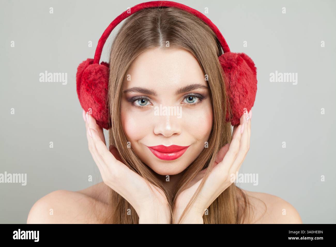 Perfect woman wearing red fluffy ear muffs blowing kiss, fashion beauty ...
