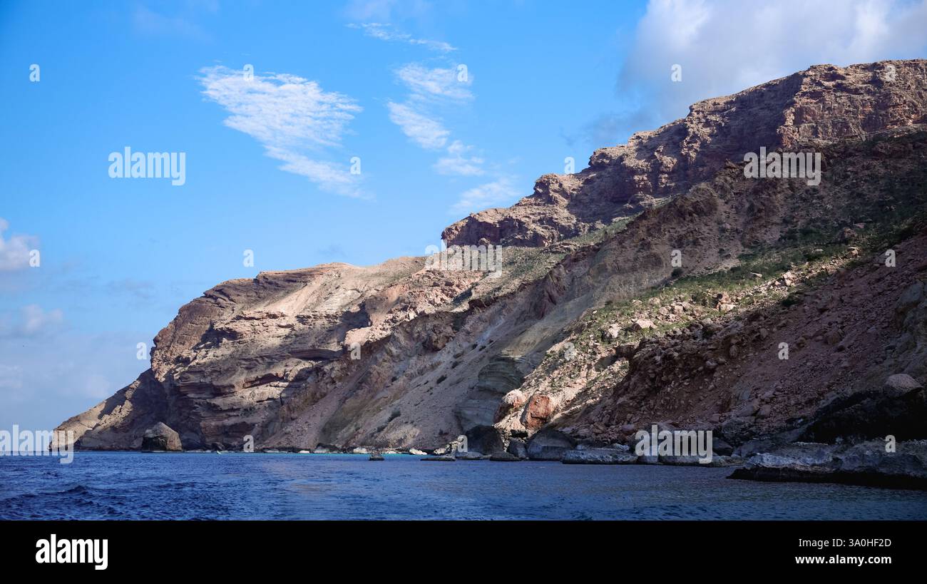 Dramatic cliffs rise above clear blue water, showcasing Socotras ...