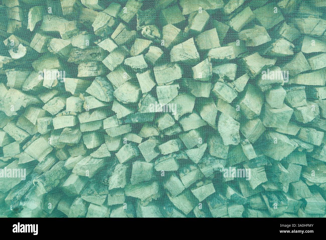 Split logs stored behind green netting Stock Photo - Alamy