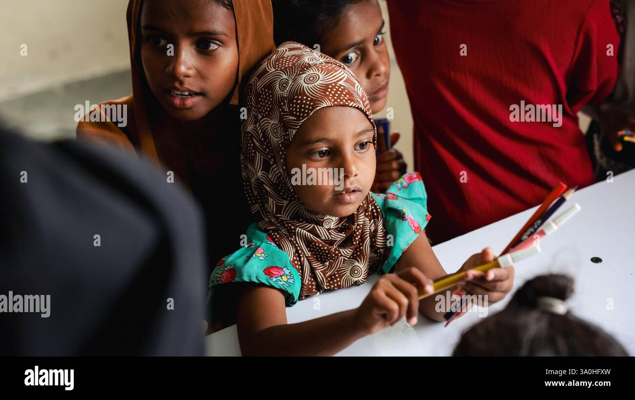 A group of children is focused on drawing and coloring with markers in ...