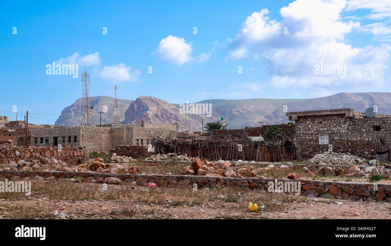 Traditional stone buildings in Socotra stand against a vibrant blue sky ...