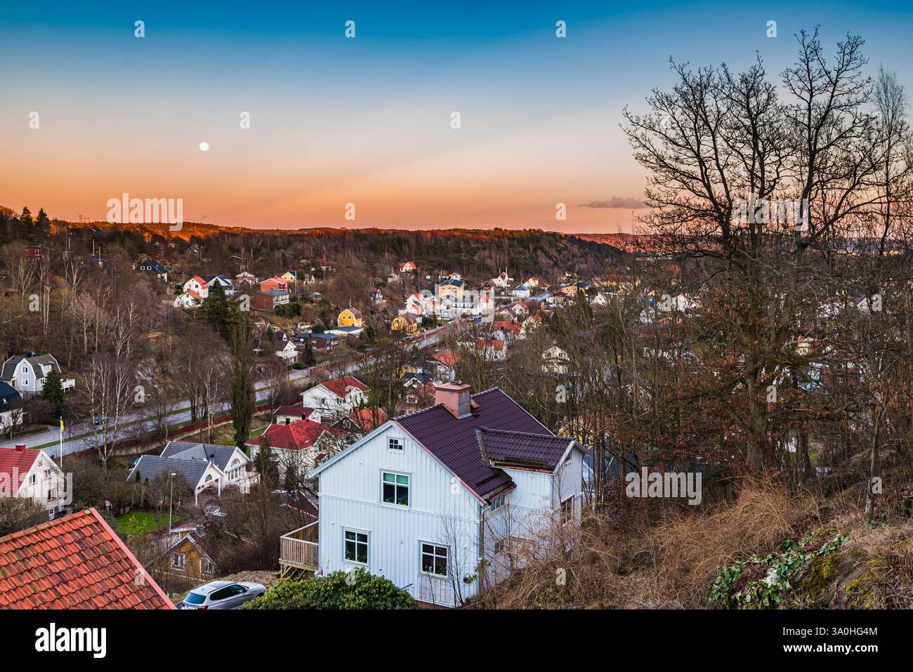 A vibrant sunset casts a warm glow over a charming Swedish village ...