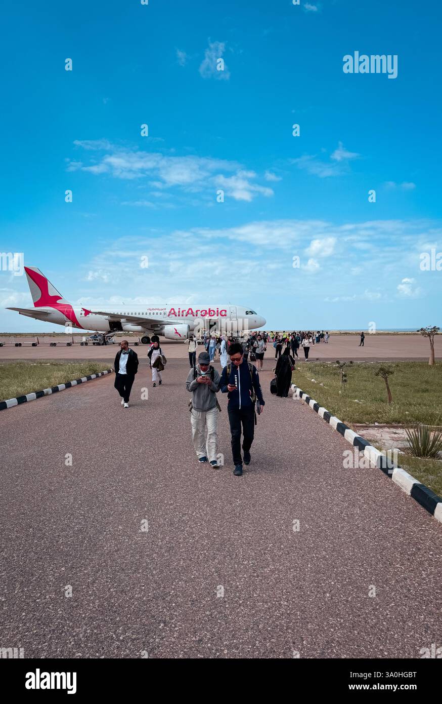 Tourists and travelers walk along the tarmac towards Socotra Airport ...