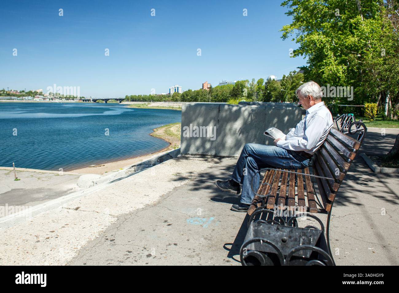 This photograph captures a peaceful scene of a man sitting on a bench ...