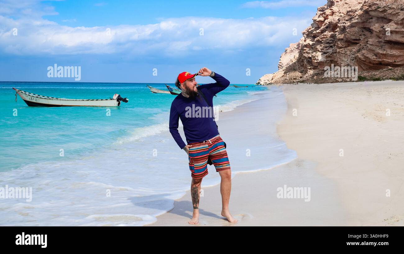 A visitor strolls along the sandy shores of Socotra, taking in the vibrant blue waters and ...