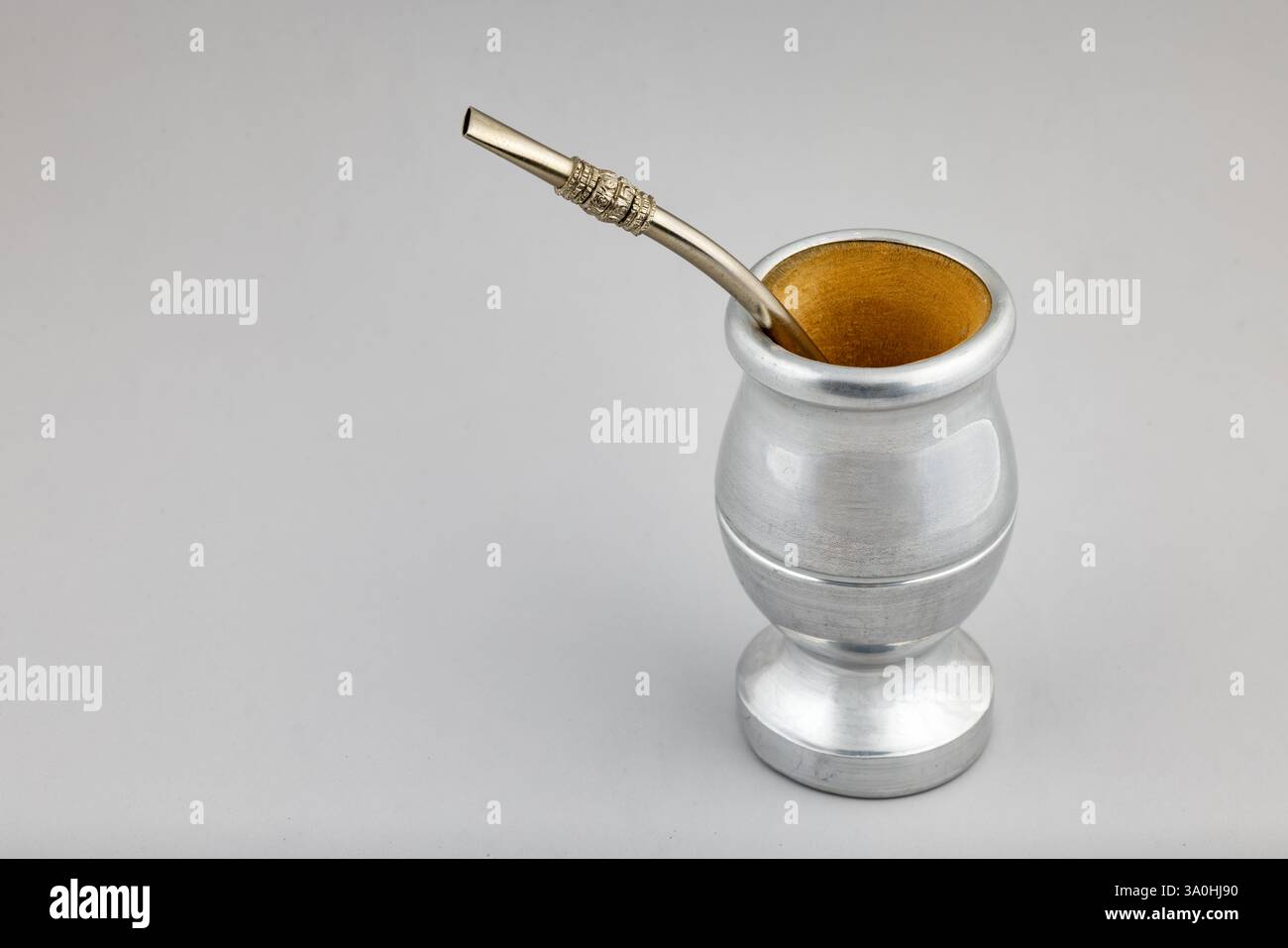 Traditional silver mate gourd with a metal straw on a clean white ...