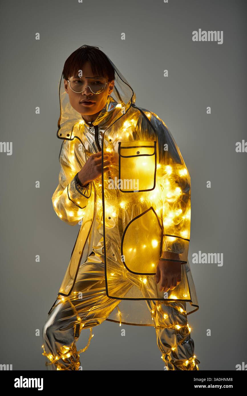 A young Asian man captivates in a modern outfit with glowing lights ...