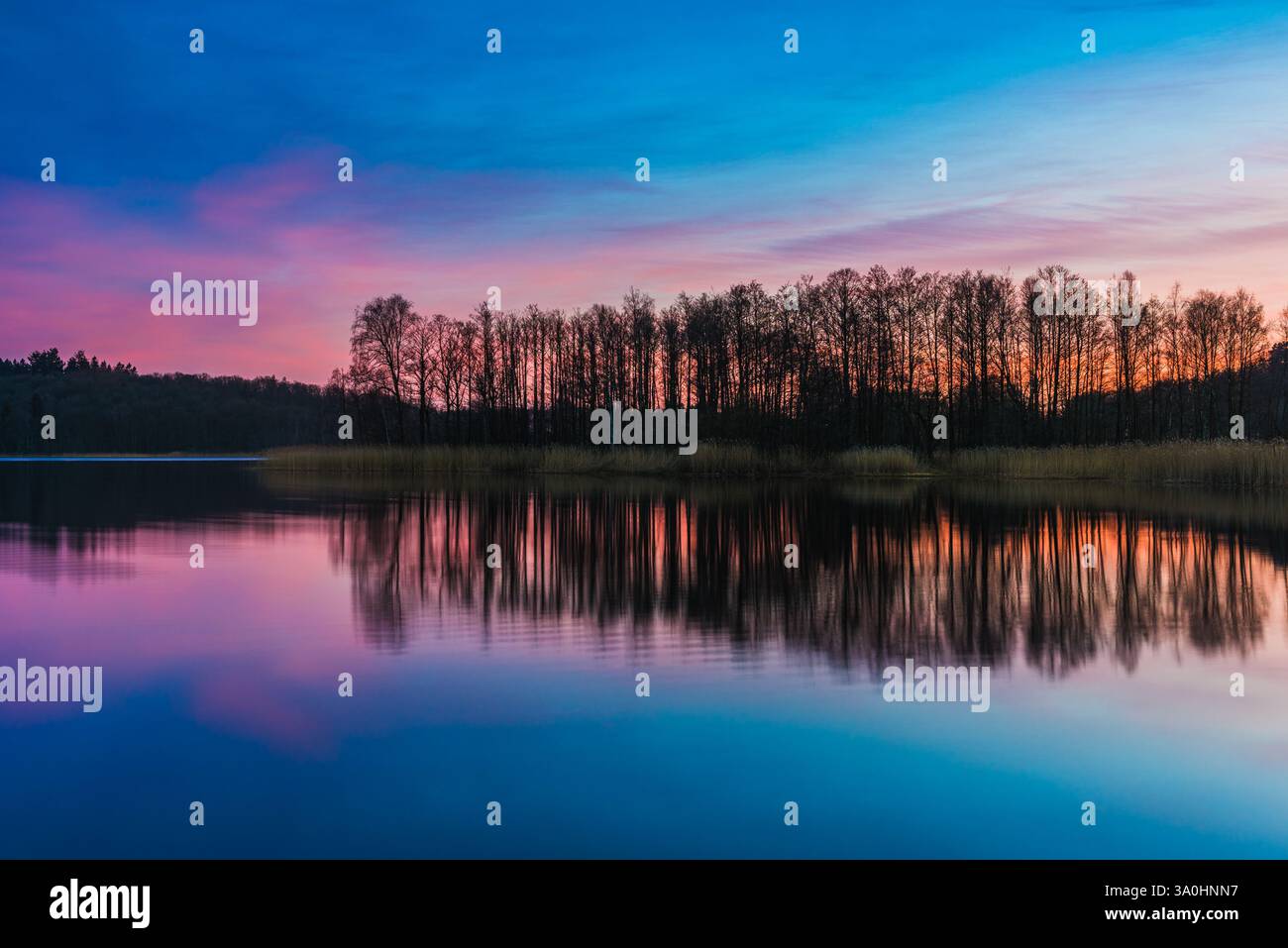 Golden and purple colors fill the sky as the sun sets behind a calm ...