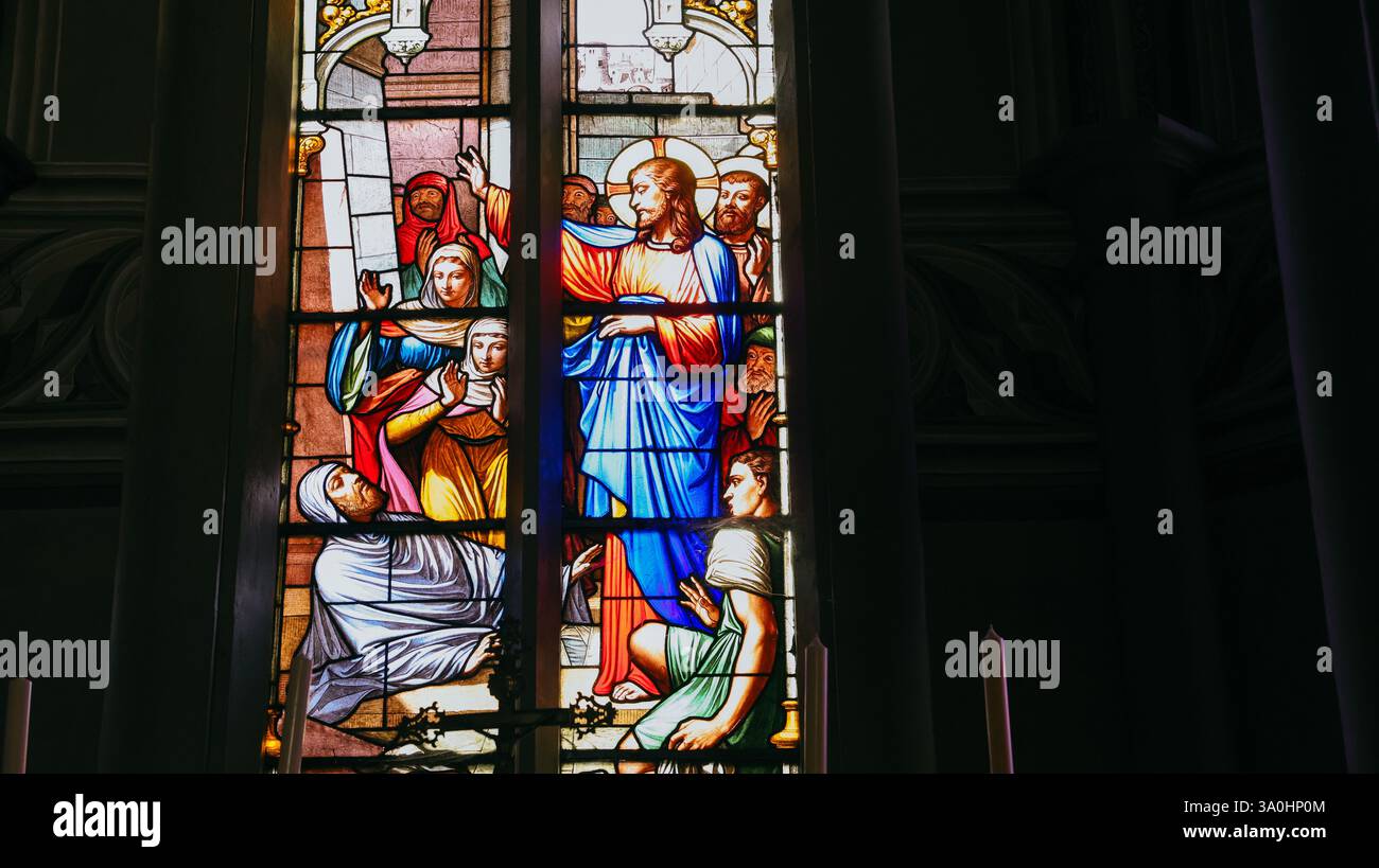 A vibrant stained glass window depicts a biblical story with figures in ...