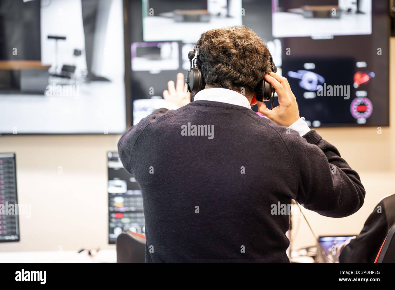 A television director in a broadcast control room, actively guiding a ...