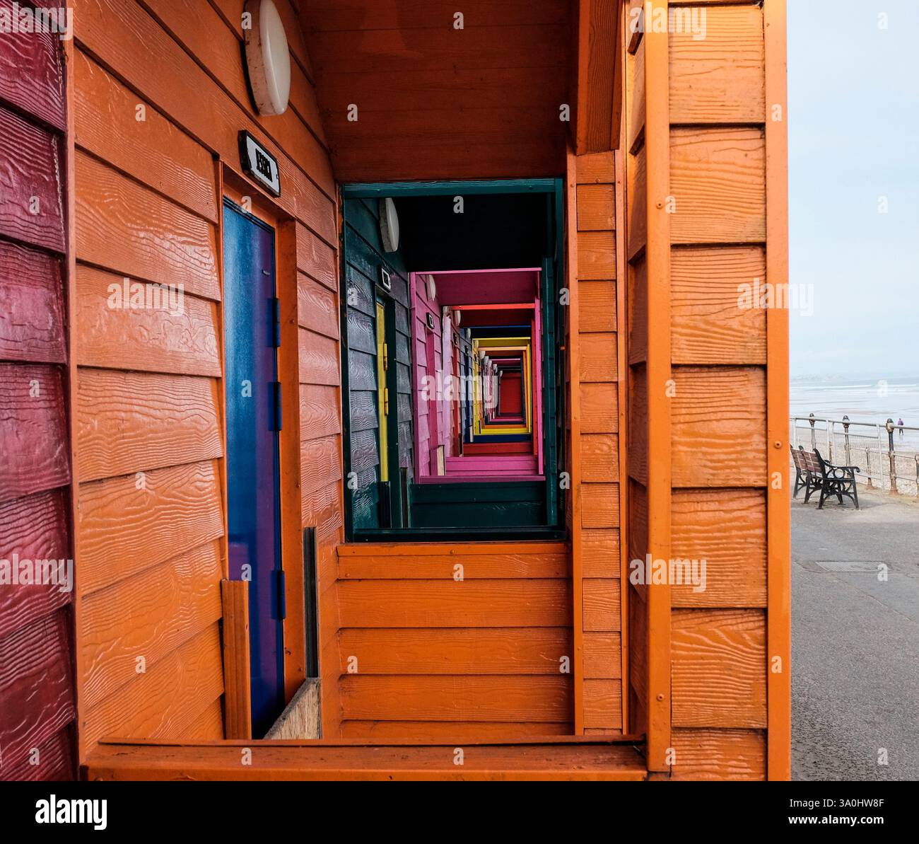 A view through a row of colourful beach huts on the esplanade in ...