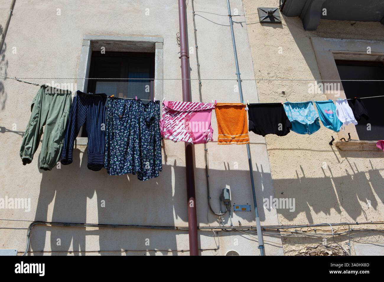 Colorful clothes drying on a line attached to a rustic building facade ...