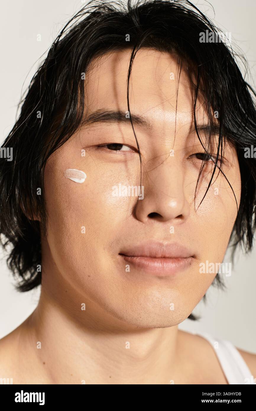 Handsome young asian man applies skincare with confidence, embodying ...