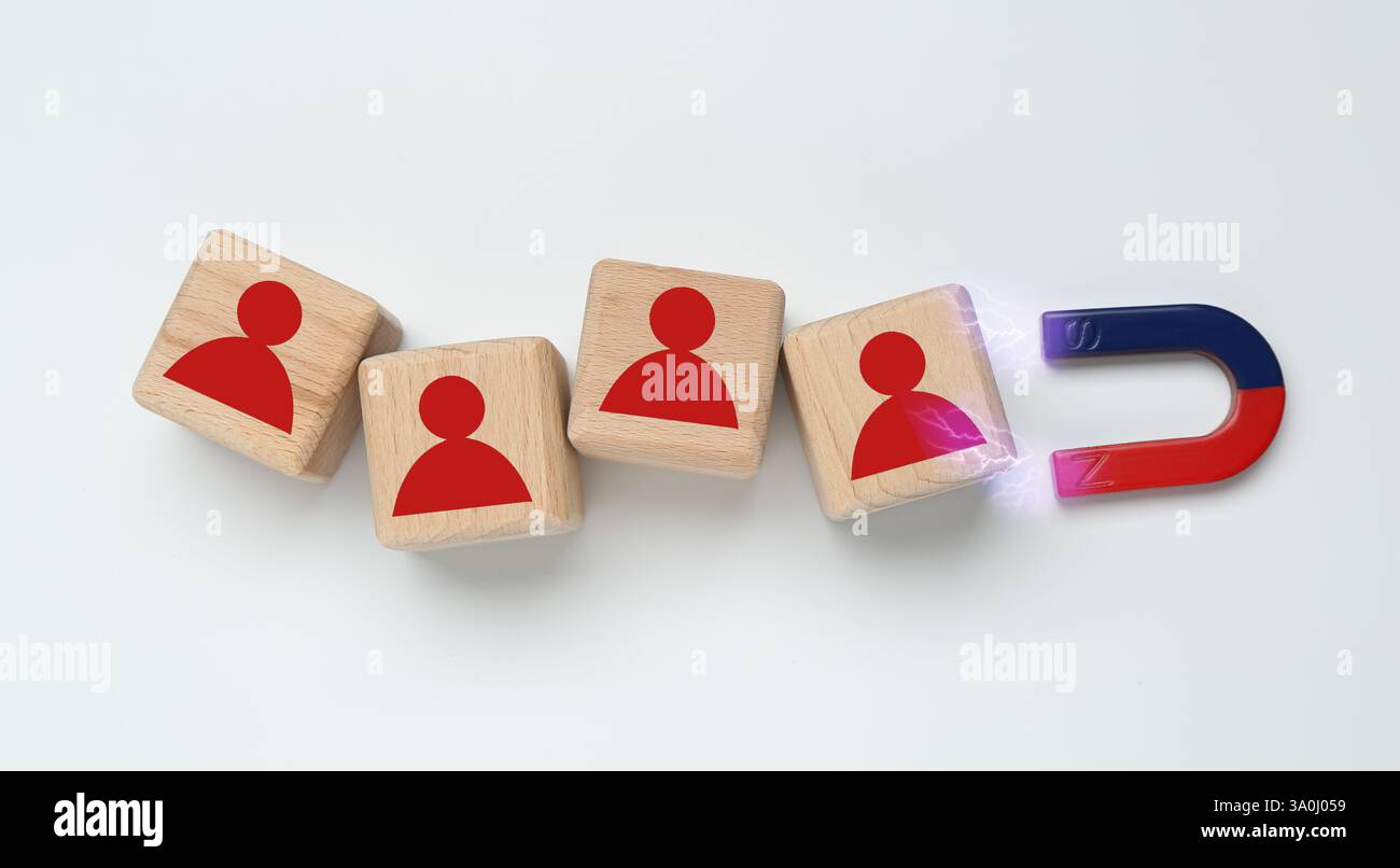 Magnet attracting wooden cubes with human figures on white background ...
