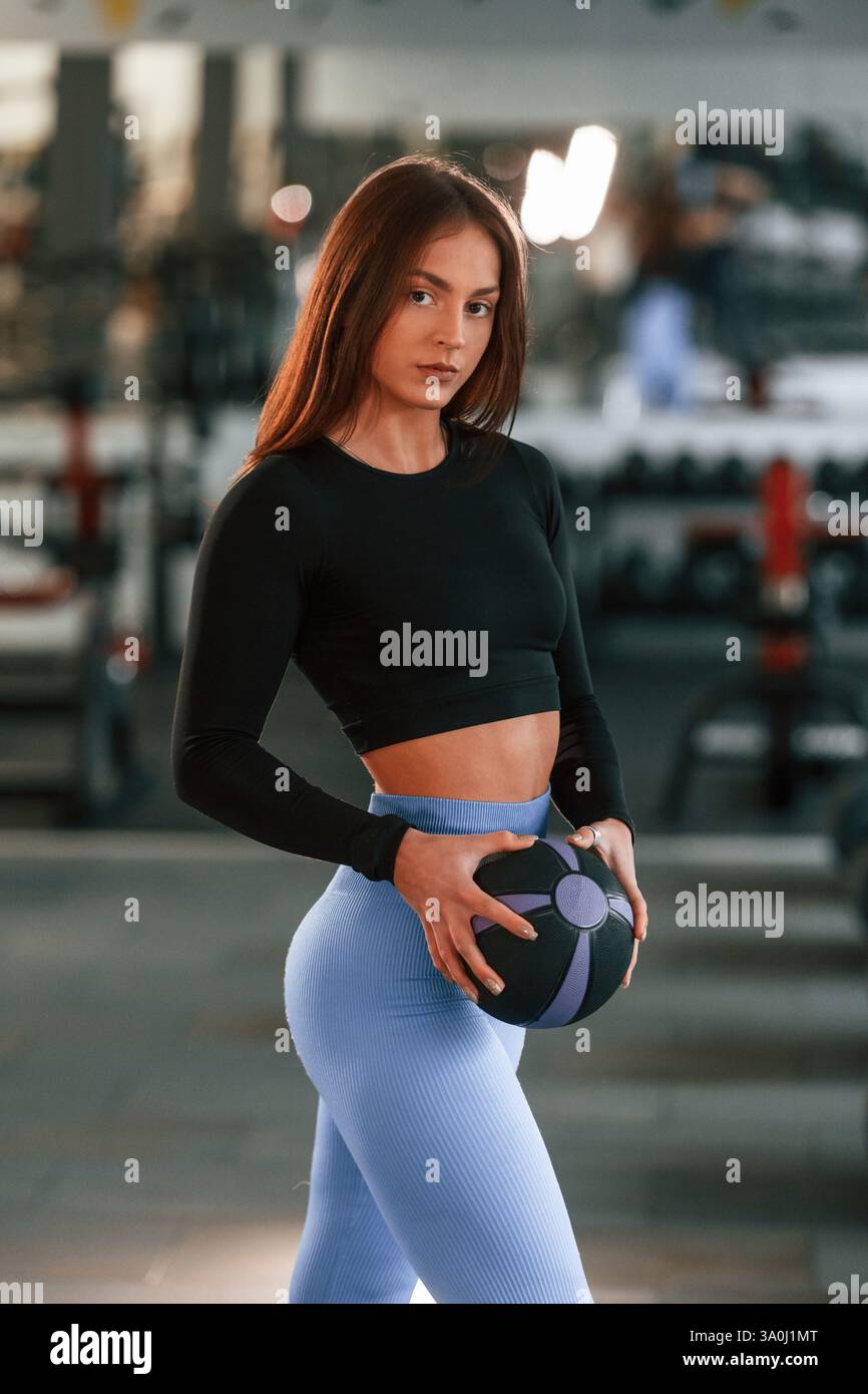 Fitness ball in hands. Standing and posing. Beautiful woman with sport ...