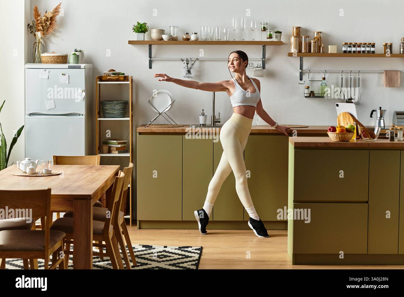 A fit young woman showcases her dance moves in a stylish kitchen ...