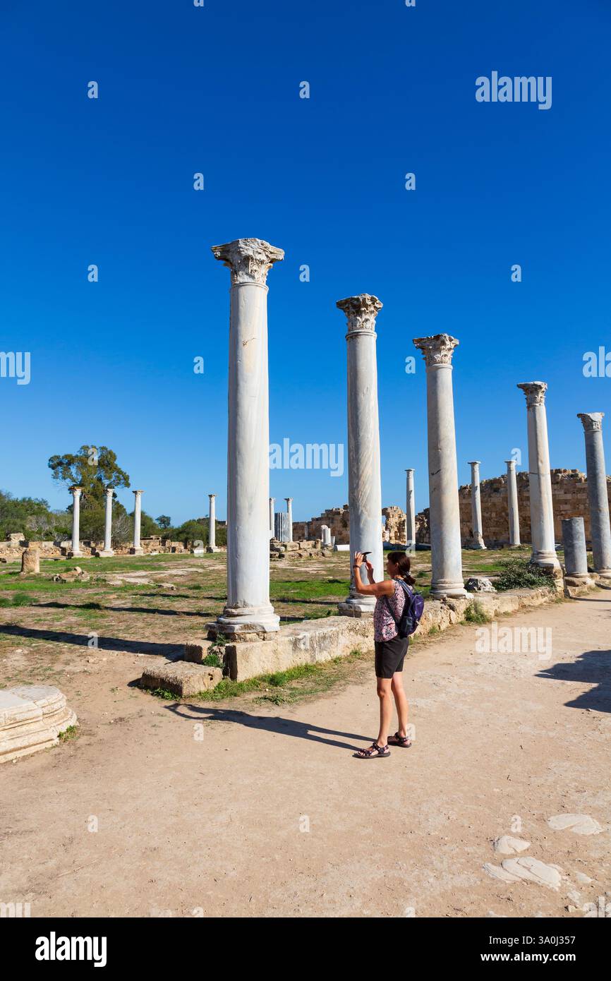 A female woman tourist in shorts, photographing at the ancient Greek ...
