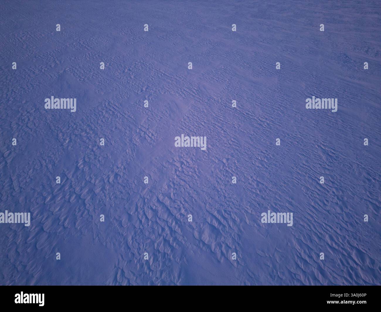 Aerial view of a textured snow-covered surface shaped by wind patterns ...