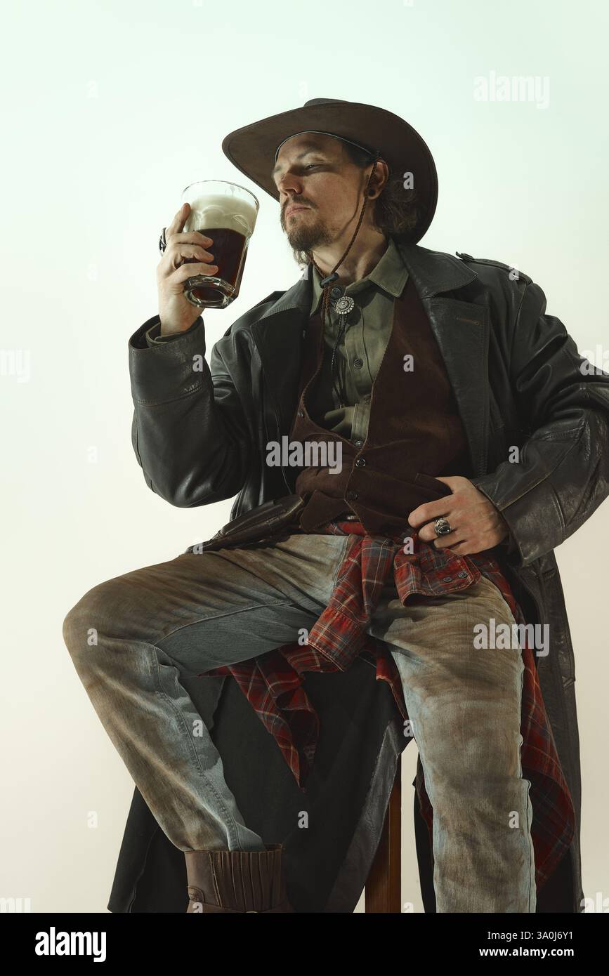Handsome man, cowboy sitting on chair and enjoying cold foamy dark beer ...