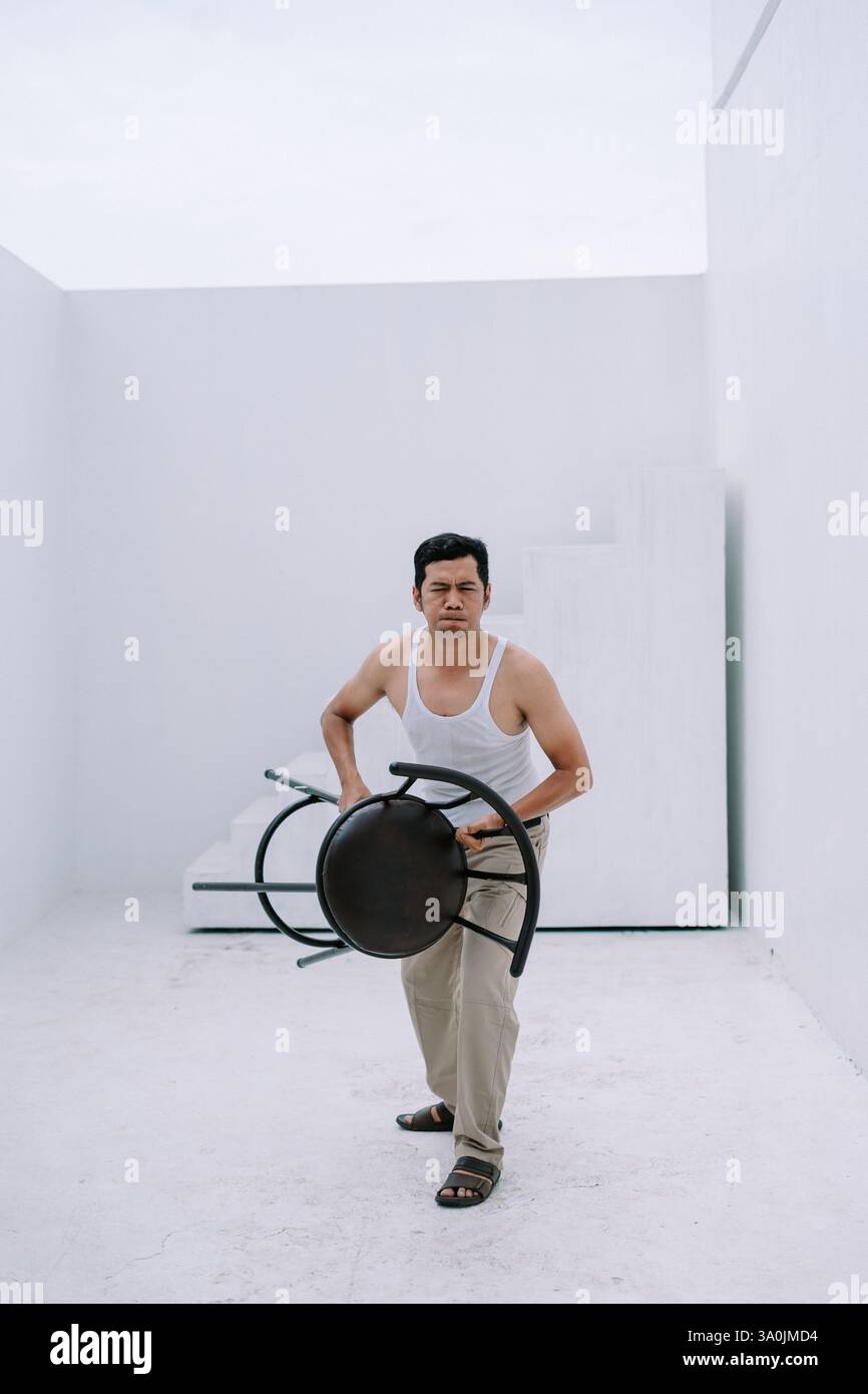 An man is captured in a moment of physical exertion, struggling to lift ...