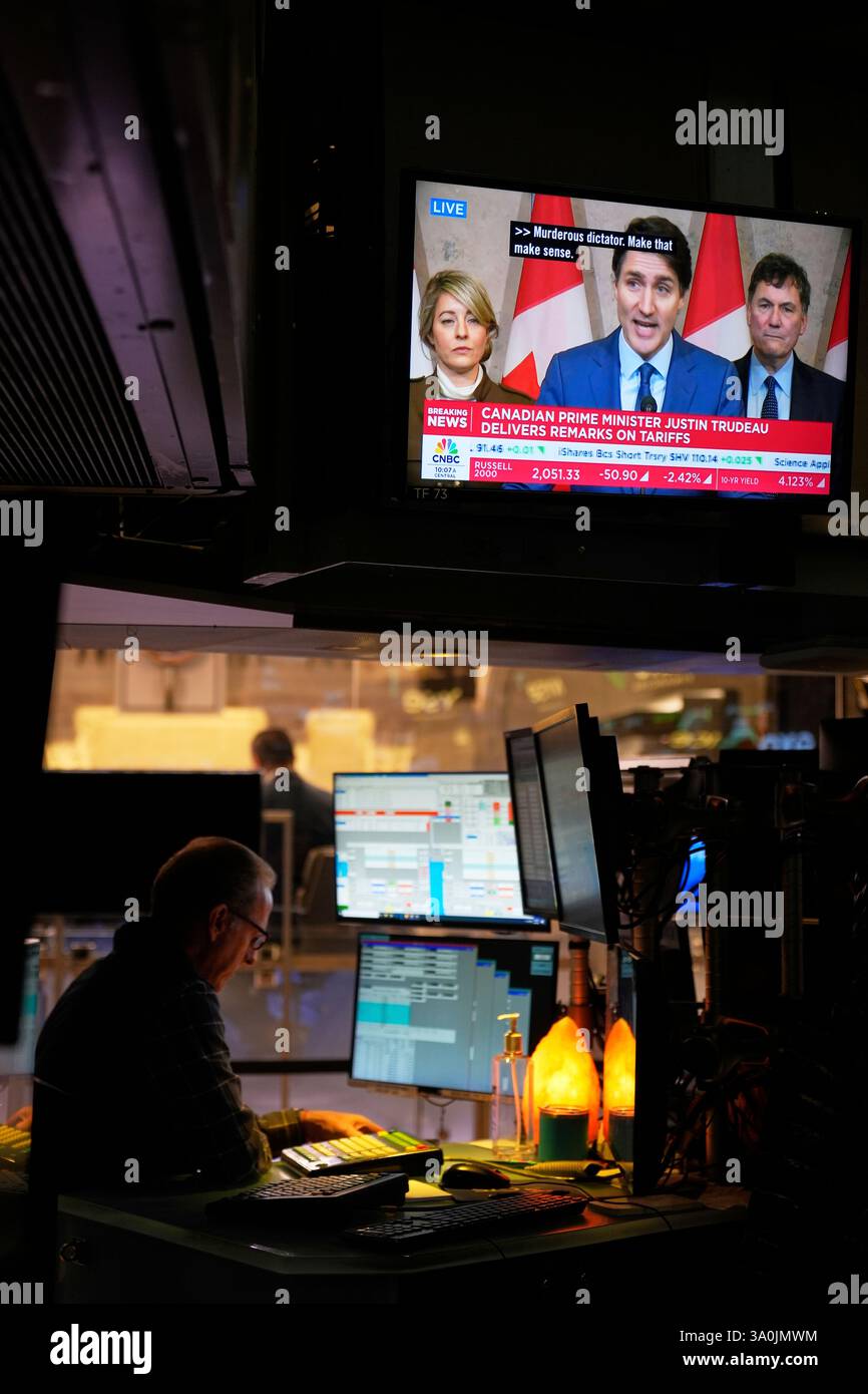 People work as a television displays a news conference by Canadian ...