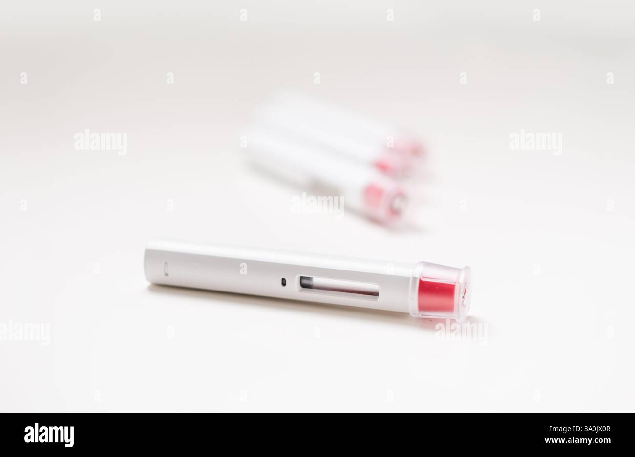 A clean an aseptic white pen injector with a red tip for biological ...